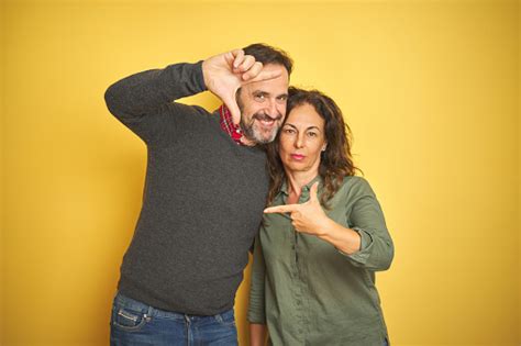 아름다운 중년 부부는 행복한 얼굴로 손과 손가락으로 프레임을 만드는 고립 된 노란색 배경 위에 미소 창의력과 사진 개념 2명에 대한 스톡 사진 및 기타 이미지 Istock