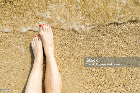 해변의 모래에 밝은 빨간 페디큐어와 아름다운 여성 발의 최고 전망 바다의 물결은 여성의 발을 낭비합니다 바닷가 휴가 동안 휴식과 즐거움 공간을 복사합니다 건강한 생활방식에