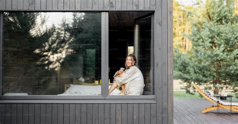 아름다운 시골집이나 호텔에서 휴식을 취하는 젊은 여성은 창틀에 앉아 소나무 숲의 아름다운 전망을 즐기고 있다 바깥에서 볼 수 있습니다 자연에 대한 고독과 레크리에이션의