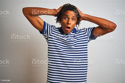 고립 된 흰색 배경 미친 위에 서 줄무늬 파란색 폴로를 입고 공포를 가진 아프로 남자 미친 머리에 손을 무서워 두려워하고 열린 입으로 충격의 놀라움 감정에 대한 스톡 사진