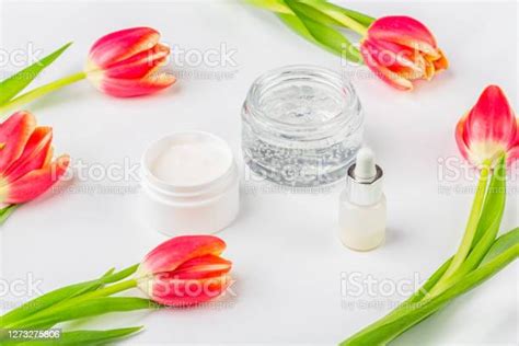천연 유기농 수제 화장품 컨셉 스킨 케어 구제 및 미용 제품 흰색 배경에 봄 빨간 튤립 꽃 사이에 크림과 세럼 용기 닫기 텍스트에 대한 공간을 복사 각질제거에 대한 스톡