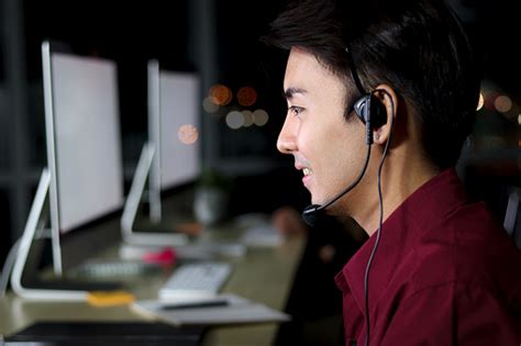 행복한 미소 짓는 아시아 남자는 밤새 팀원 동료와 함께 일하는 콜센터 서비스 컨설턴트에서 일하고 마이크 헤드셋을 가진 야간 근무 고객 서비스 직원은 지원 고객을 위해