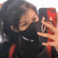A Woman Taking A Selfie While Wearing A Mask And Holding A Cell Phone Up To Her Face
