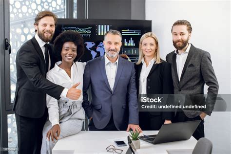 카메라를 보고 미소짓는 성공적인 창의적인 다민족 비즈니스 팀의 초상화 다양한 남성과 여성 사업가는 노트북과 테이블 근처에 함께 서 공식적인 착용에 사업가에 대한 스톡 사진