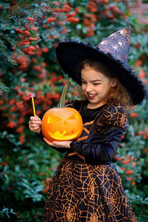 Cute Girl Of 8 9 Years In A Suit For Halloween With Pumpkin And Magic Wand Into Hands Stock