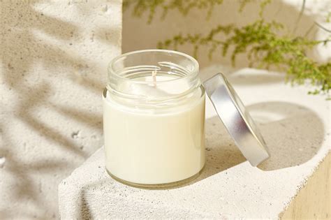 콘크리트 연단의 항아리에 향기로운 양초가있는 미적 구성 자연 스타일의 모형 콩 왁스 양초 녹색 잎이 달린 향긋한 수제 양초 유리에 콩 왁스에서 수제 스파 제품 촛불 조명