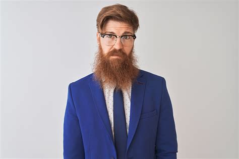 젊은 빨간 머리 아일랜드어 사업가 얼굴에 심각한 표정과 고립 된 흰색 배경 위에 양복과 안경을 착용 카메라를 보는 간단하고 자연스러운 결심에 대한 스톡 사진 및 기타 이미지
