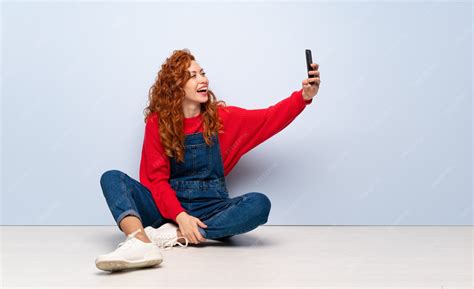 Premium Photo Redhead Woman With Overalls Sitting On The Floor Making