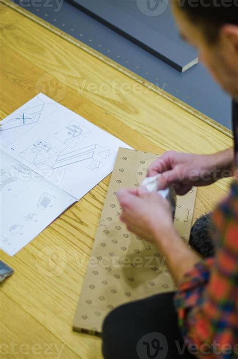 Man Assembling Furniture With Instruction Manual On Wooden Floor High Quality Photo 52909963