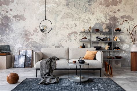 회색 디자인의 소파 커피 테이블 책꽂이 보행 램프 카펫 장식 우아한 액세서리가 있는 현대적인 아파트의 로프트 스타일 콘크리트 그런지 벽 템플렛 0명에 대한 스톡 사진 및