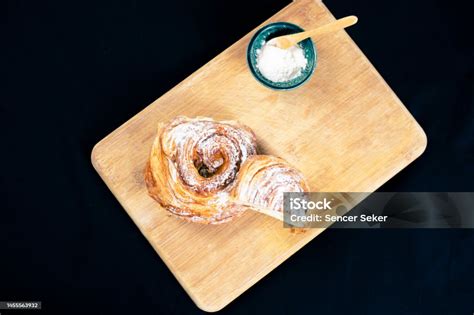 검은 배경에 유럽식 아침 식사 나무 도마에 가루 설탕이 든 크로와상이 있습니다 에스카르고 또는 페인 루스라고도 하는 페인 Aux 건포도는 커스터드 크림과 건포도를 곁들인