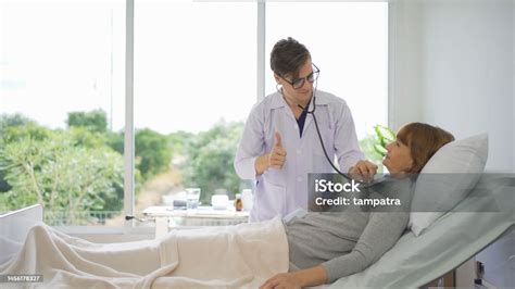 백인 의사의 초상화는 요양원이나 클리닉에서 의료 및 건강 관리 치료를 위해 병원의 침대에서 아픈 환자의 시체를 확인합니다 사람들의 라이프 스타일 2명에 대한 스톡 사진 및