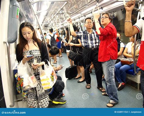 commuters or passengers inside the mrt pass the time by playing games