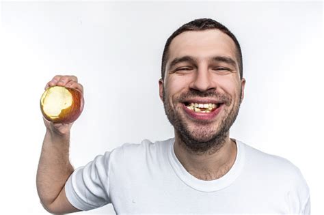 행복 하 고 기쁜 젊은 남자는 그가 치아와 잇 몸에 문제가 없는 것을 기쁘게 생각 합니다 그들은 깨끗 하 고 건강 하 고 좋은 또한 그는 사과 한 조각을 물린 있다 흰색