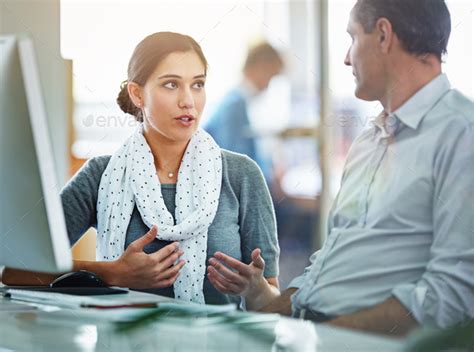 Shot Of Designers Talking Together At A Workstation In An Office Stock