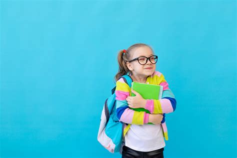 줄무늬 재킷과 배낭에 안경을 가진 귀여운 어린 소녀의 초상화 교육의 개념 사진 스튜디오 파란색 배경 텍스트 장소 6 7 살에 대한 스톡 사진 및 기타 이미지 Istock