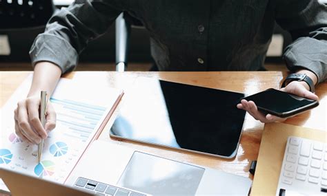 이 마운트에서 여성 펜 포인팅 그래프 차트와 다음 달 품질을 개선하기 위해 계획에 스마트 폰을 사용합니다 Brand Name Smart Phone에 대한 스톡 사진 및 기타