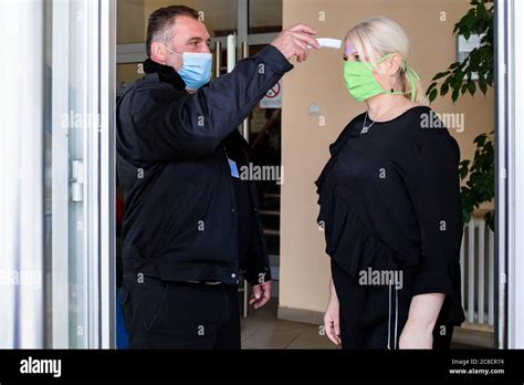Male Security Measuring Body Temperature Of Female Worker On The Entrance Stock Photo Alamy