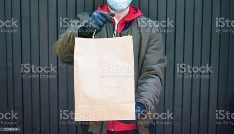 의료 용 고무 장갑과 마스크에 공예 종이 패키지 가방을 들고 배달 남자 빠르고 무료 배달 운송 온라인 쇼핑 격리 서비스 공간을