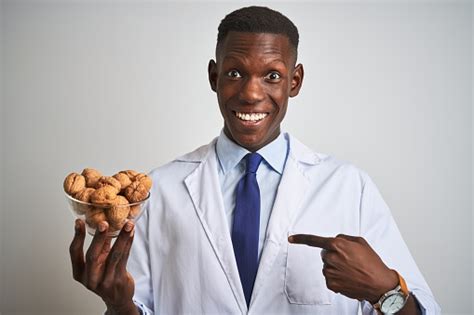 자신에게 손가락을 가리키는 깜짝 얼굴과 고립 된 흰색 배경 위에 서 호두와 그릇을 들고 아프리카 계 미국인 의사 남자 가리키기에 대한 스톡 사진 및 기타 이미지 Istock