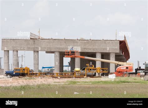 Hard Hat Worker Stands In Basket Of Boom Lift During Bridge Construction Over Highway In