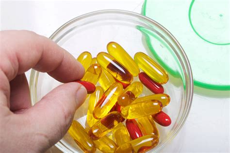 남자는 그의 손에 약을 들고 있다 빨간색과 노란색의 알 약은 플라스틱 뚜껑이 있는 유리 용기에 에 흰색 표면 위에서 볼 수 있습니다 0명에 대한 스톡 사진 및 기타 이미지