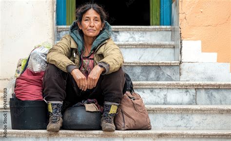 Homeless Woman Sitting With Her Belongings On The Steps Of An Old