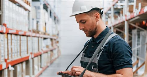 태블릿에서 데이터를 확인합니다 제복을 입은 직원이 낮에 창고에서 일하고 있습니다 사진 Unsplash의 검사 이미지