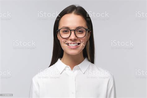 흰색 칼라 셔츠를 입고 안경을 쓰고 미소짓는 여성 행복한 미소로 시청자를 바라보며 자신감과 도움을 줄 준비가 된 모습 회색