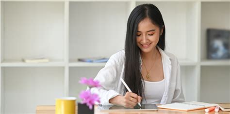 스타일러스 펜으로 컴퓨터 태블릿에 그리기 스케치하는 세련된 여성의 자른 이미지는 편안한 거실 을 배경으로 나무 작업 책상에 앉아