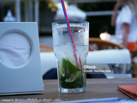 카페의 여름 베란다에는 얼음이 든 차가운 모히토 한 잔이 테이블 위에 있습니다 튜브가있는 유리는 응축수 방울로 덮여 있습니다 더운 여름날에 마십니다 0명에 대한 스톡 사진