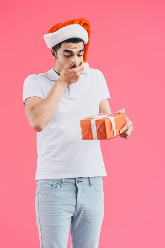 산타 모자 선물 상자를 들고와 핑크 새 해 개념에 고립 된 입 취재에 충격된 잘생긴 남자 T Lounge에 대한 스톡 사진