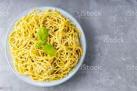 페스토 소스를 곁들인 스파게티와 회색 배경에 간 파마산 치즈 소스 페스토와 바질 잎을 화이트 플레이트에 곁들인 이탈리아 파스타 공간을 복사합니다 위쪽 보기 강판에 갈기에
