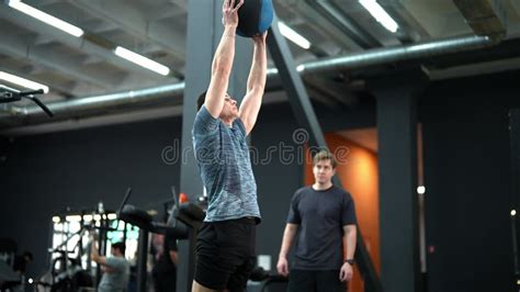 Tilt Up Shot Of Personal Trainer Showing Explaining Correct Execution To Beginner Sportsman How