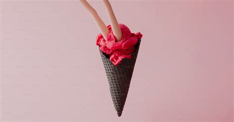 분홍색 파스텔 배경에 검은 원뿔이 있는 빨간 아이스크림에 인형 다리 창조적 인 여름 개념입니다 사진 Unsplash의