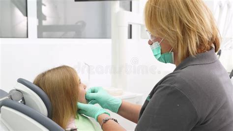 Female Dentist Preparing Girl For Teeth Examination In Modern Dental