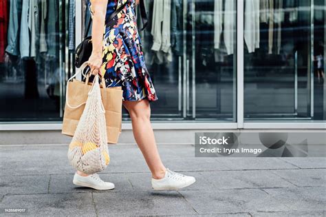 지속 가능한 친환경 슬로우 패션 쇼핑 흰색 재사용 가능한 캔버스 그물 가방과 종이 쇼핑백을 옷 가게 배경에 가진 여자의 얼굴 없는 초상화 토트백에 대한 스톡 사진 및 기타