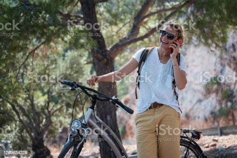 자전거를 타고 아름다운 젊은 여성이 숲속의 스마트폰으로 말합니다 여름 방학 및 사이클링 스포츠 및 야외 활동 Trekking Bike에 대한 스톡 사진 및 기타 이미지