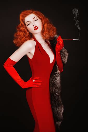 빨간 드레스에 긴 장갑 검은 배경에 연기 곱슬 머리와 빨간 머리 여자 여자는 옷을 입고 자연 모피와 레트로 스타일과 하얀 치아와