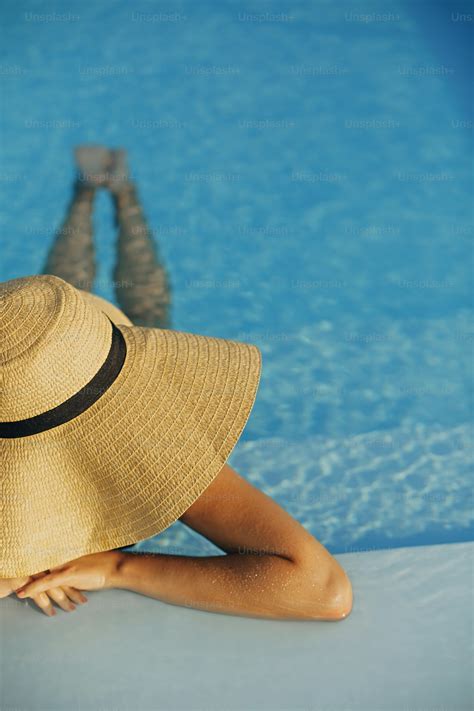 모자를 쓴 세련된 젊은 여성이 푸른 수영장에서 휴식을 취하고 여름 휴가를 즐기고 있다 고급 리조트에서 휴가를 보내는 햇볕을 쓴 소녀 옥상의 수영장에서 수영 최고의 전망