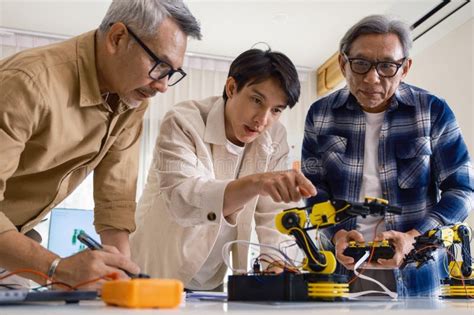 Asian Robot Arm Engineers Brainstorming In Workshop To Develop Control Technology With Teamwork