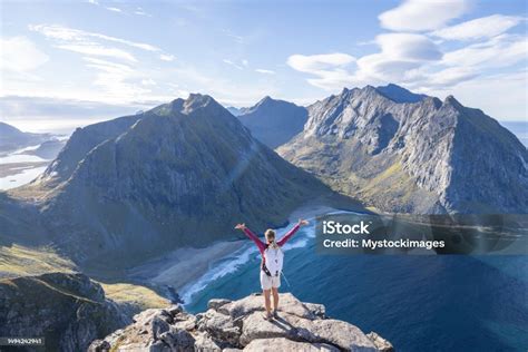 여성 등산객은 로포텐 섬의 매달린 바위 팔 해변 산 전망에 서 있습니다 멀리 떨어진에 대한 스톡 사진 및 기타 이미지 멀리