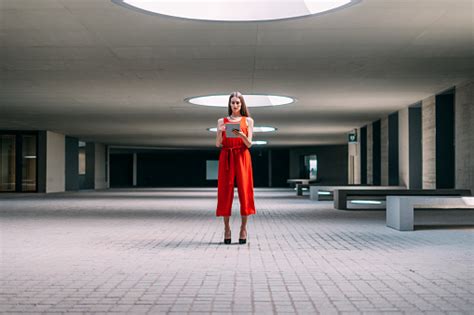 빨간 드레스를 입은 사업가가 디지털 태블릿으로 작업합니다 그녀는 현대 환경에 서 있다 인물 사진 20 24세에 대한 스톡 사진 및 기타 이미지 Istock