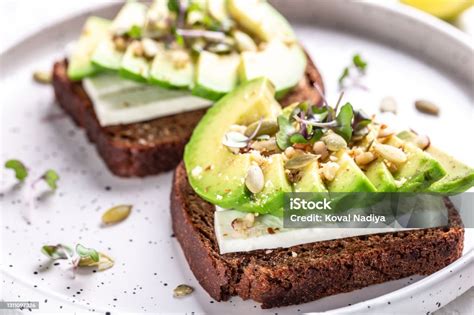호밀 빵 얇게 썬 아보카도 치즈 호박 견과류 참깨를 곁들인 건강한 아보카도 토스트를 아침 또는 점심 식사로 만드시면 좋습니다 채식 음식 비건 메뉴 음식 조리법 배경 클로즈업