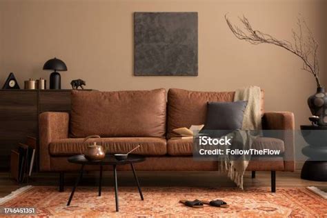 갈색 소파 둥근 커피 테이블 책 슬리퍼 검은 사다리 공 무늬가 있는 카펫 베개 및 개인 액세서리가 있는 아늑한 거실의 인테리어 디자인 가정 장식 템플렛 0명에 대한 스톡