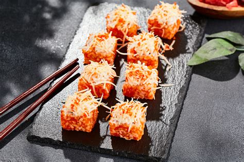 어두운 돌 테이블에 마키 초밥 토비코와 캘리포니아 마키 스시 롤 안에 생선 마구로와 치즈 바깥쪽 검은 배경 나뭇잎 및 단단한 그림자가있는 스타일 컨셉 일본 메뉴 0명에 대한