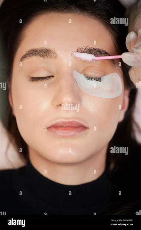 Woman With Eye Patch Under Lower Eyelid Keeping Eyes Closed While Beautician Applying Cleansing