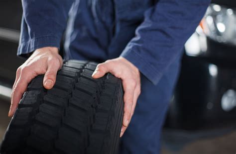 자동차 차고에서 차량 수리를 하기 위해 새 자동차 타이어를 들고 있는 정비사 45 49세에 대한 스톡 사진 및 기타 이미지 45 49세 검사 보기 고급 Istock
