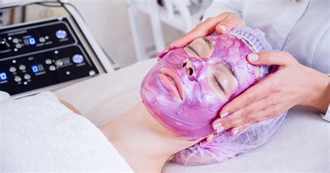 이마의 피부를 마사지하는 미용사 얼굴 관리를위한 화장품 절차에 스파 살롱에서 여성 미용사는 여성에게 얼굴에 치료 크림을 바르고