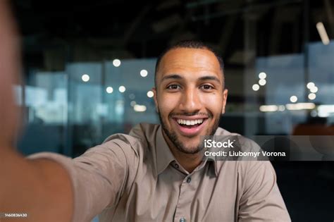 비디오 벨소리 동료들과 원격으로 이야기하는 스마트폰 카메라를 보고 있는 성공적인 사업가 사무실 내에서 직장에서 웃고 있는 히스패닉 남자 웹캠 보기 Pov 셀카에 대한 스톡